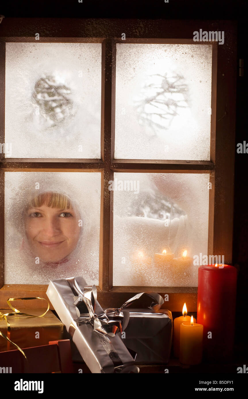 Austria, Salzburger Land, Young woman looking through window, christmas ...