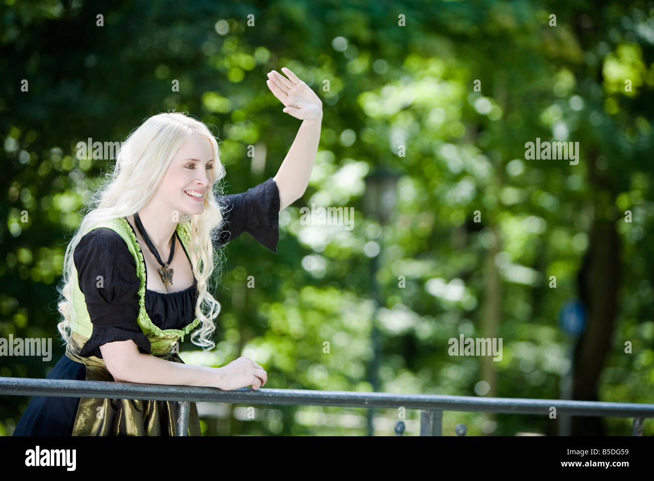 Germany, Bavaria, Munich, English Garden, Young woman waving hands ...