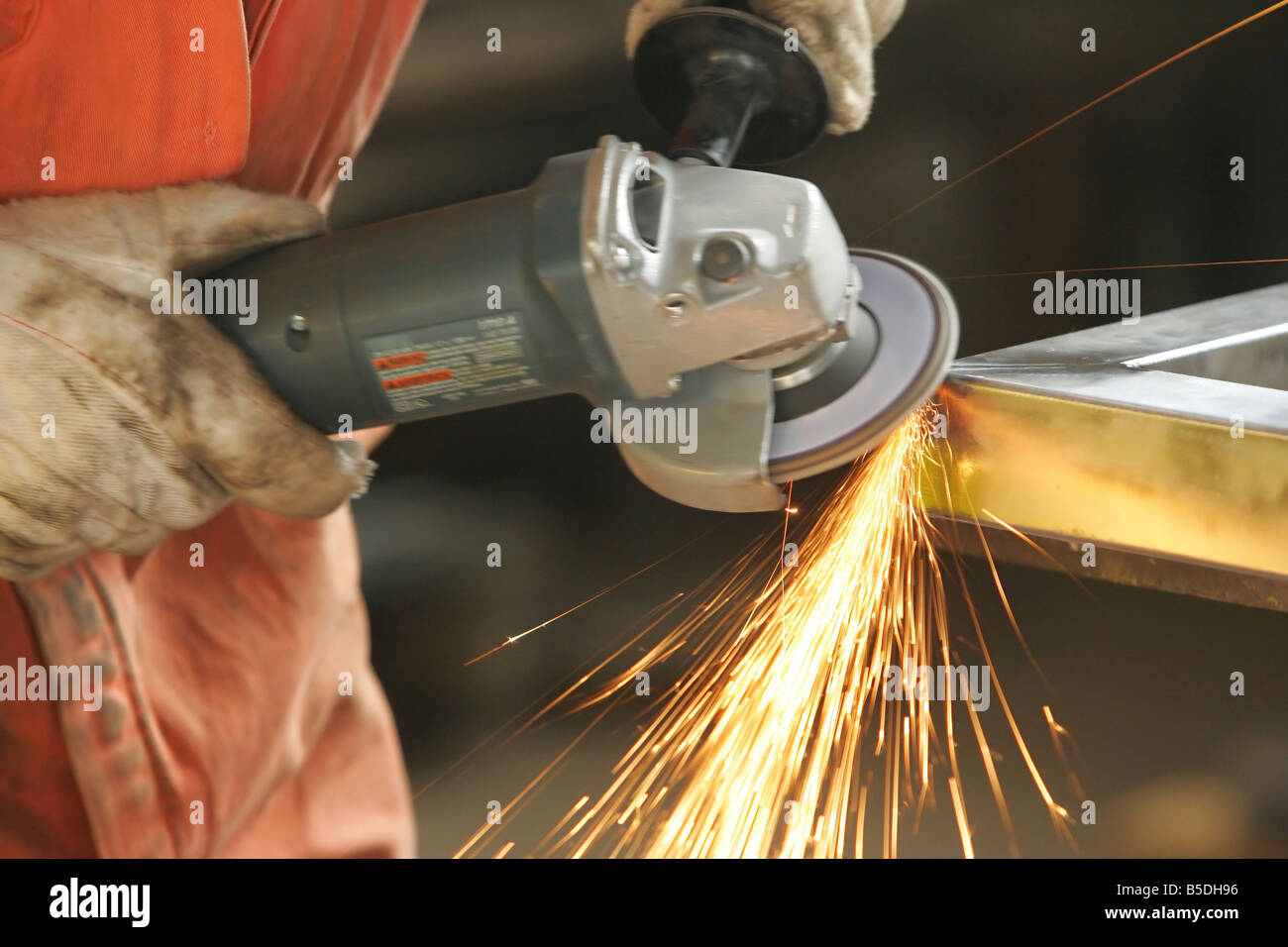 A warehouse worker grinding a corner of a weld with sparks flying Stock ...