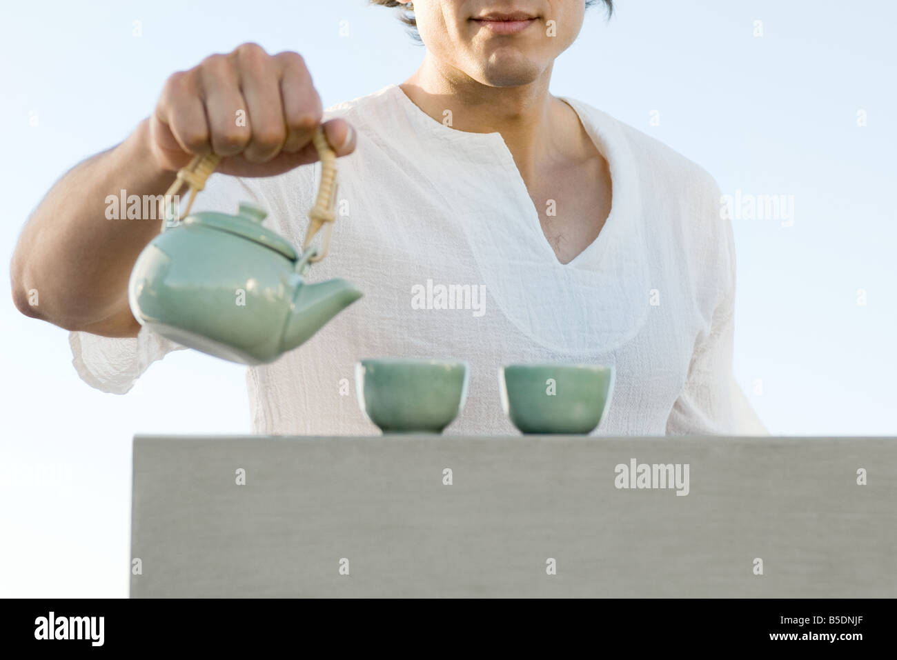 Man holding teapot, cropped, mid section Stock Photo - Alamy