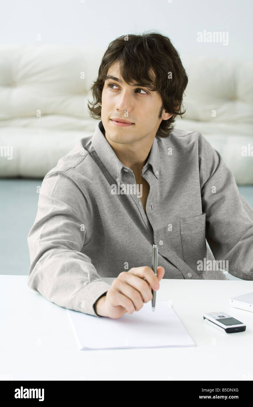 Man holding pen above paper, looking away Stock Photo - Alamy