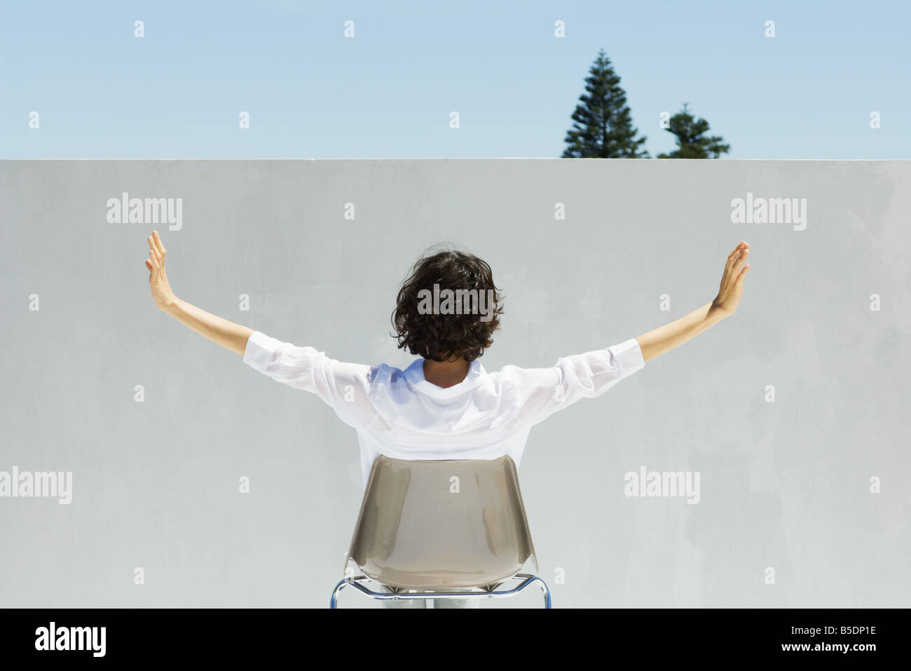 Woman seated facing wall, arms outstretched, rear view Stock Photo - Alamy