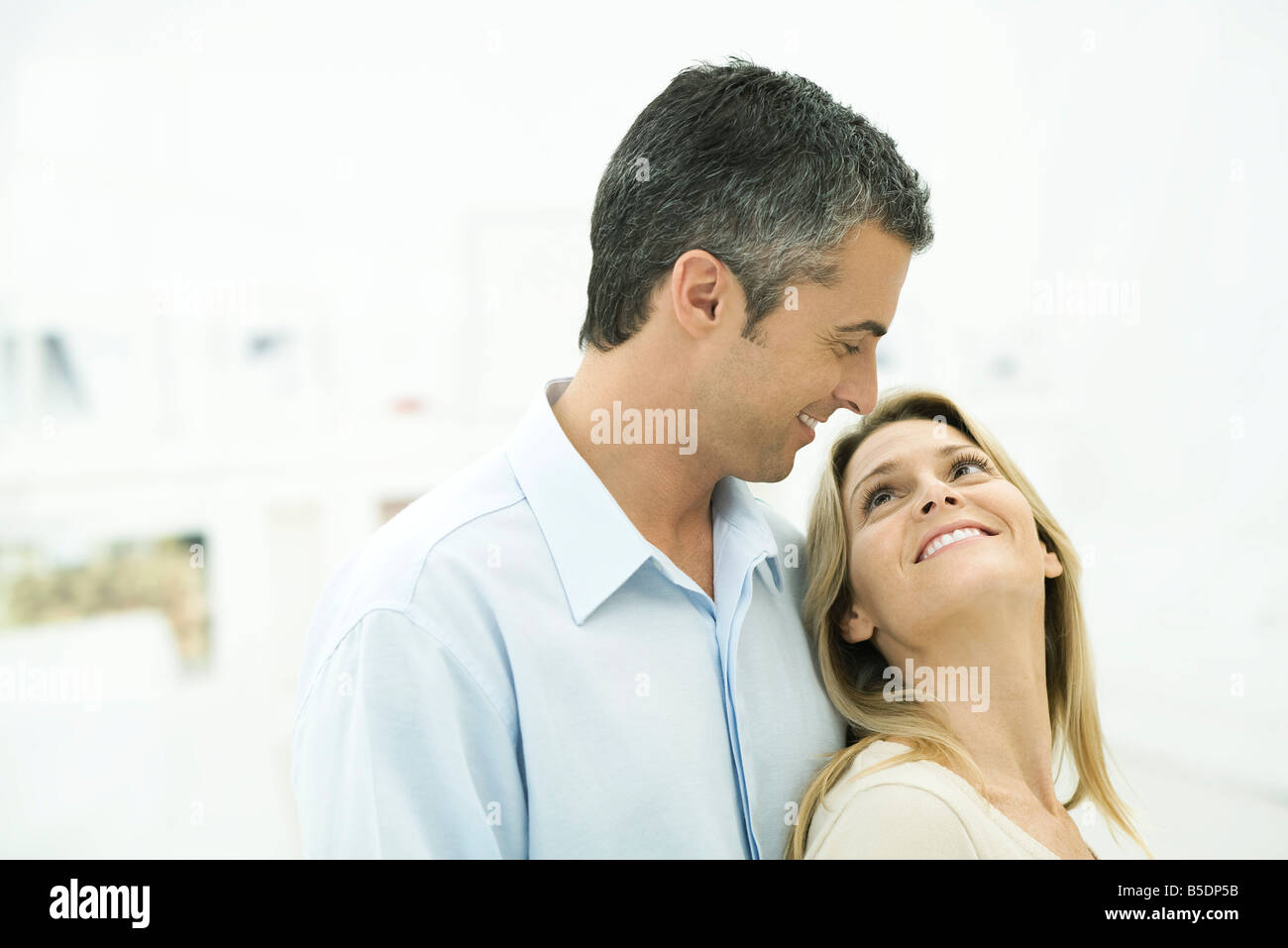 Couple smiling at each other, woman leaning against man Stock Photo - Alamy