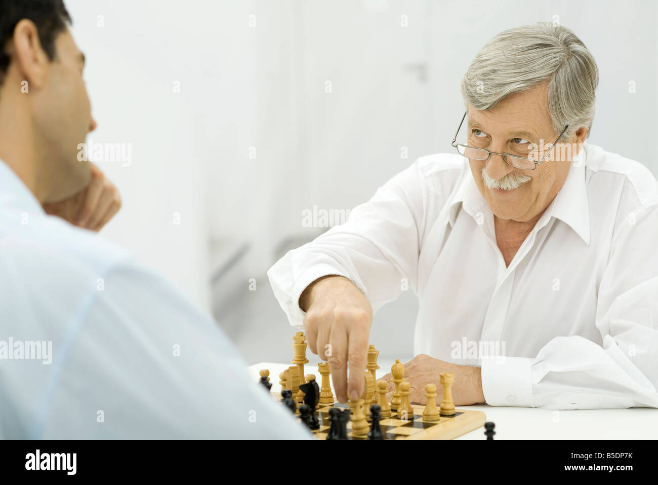 Father playing chess with adult son, smirking Stock Photo - Alamy
