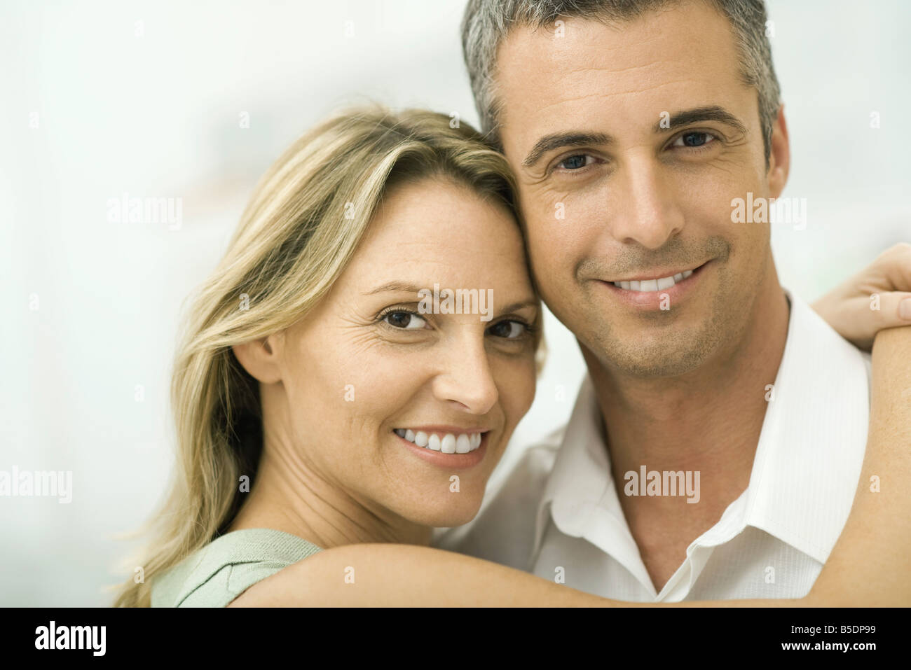 Couple smiling at camera, woman wrapping arms around man, portrait ...
