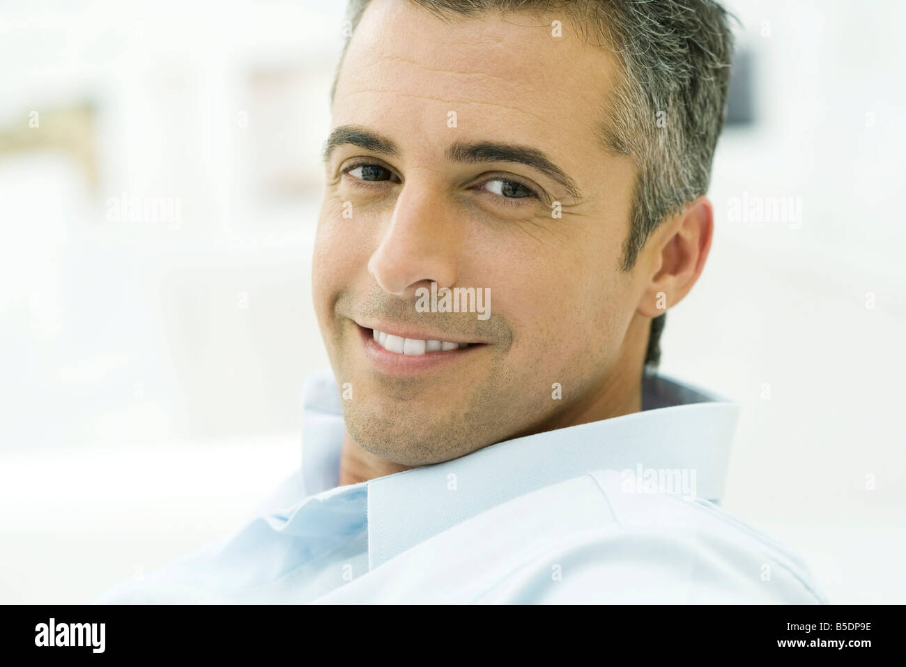 Man smiling at camera, looking over shoulder, portrait Stock Photo - Alamy