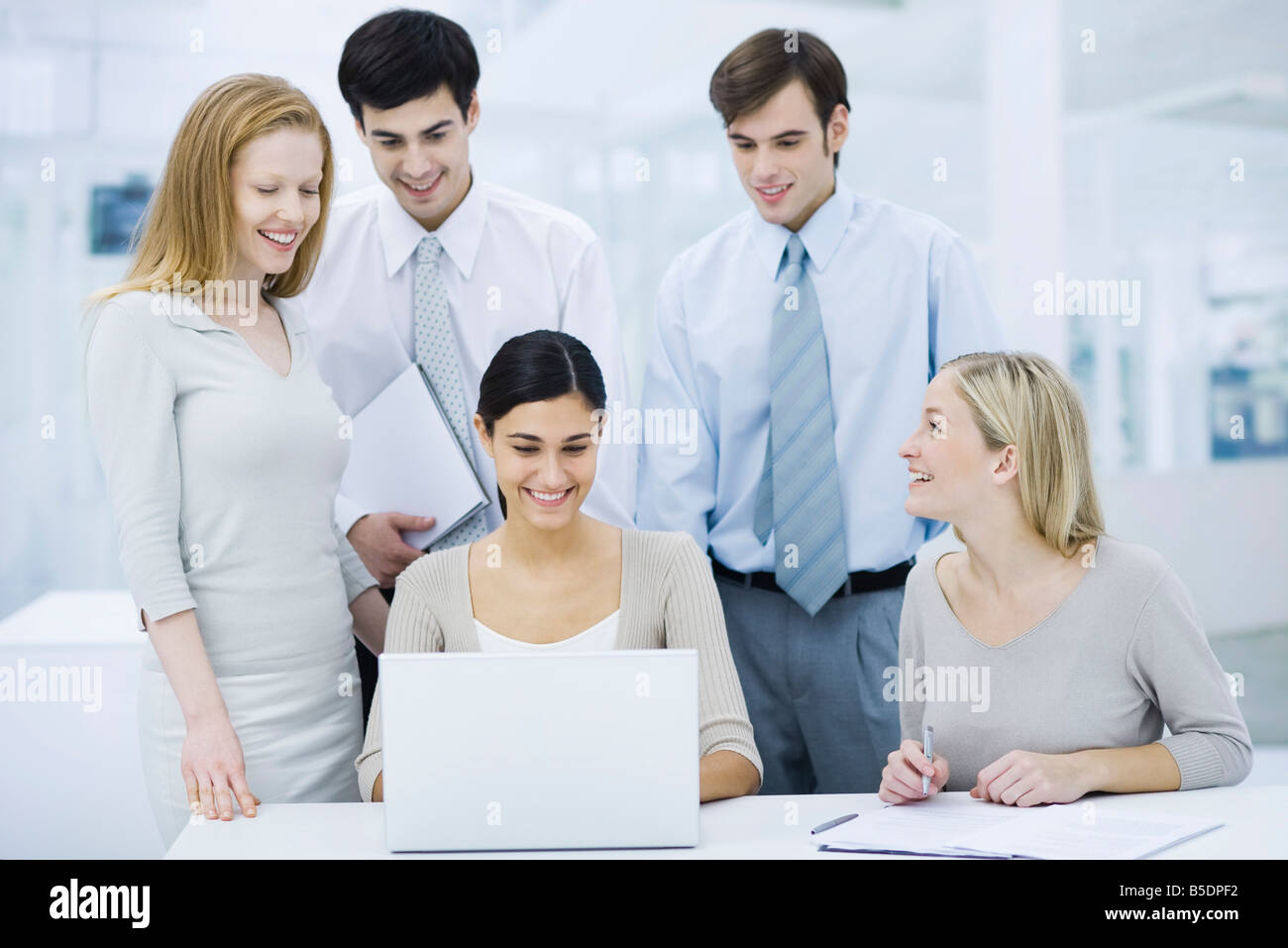 Group of professionals gathered around laptop computer, smiling Stock ...