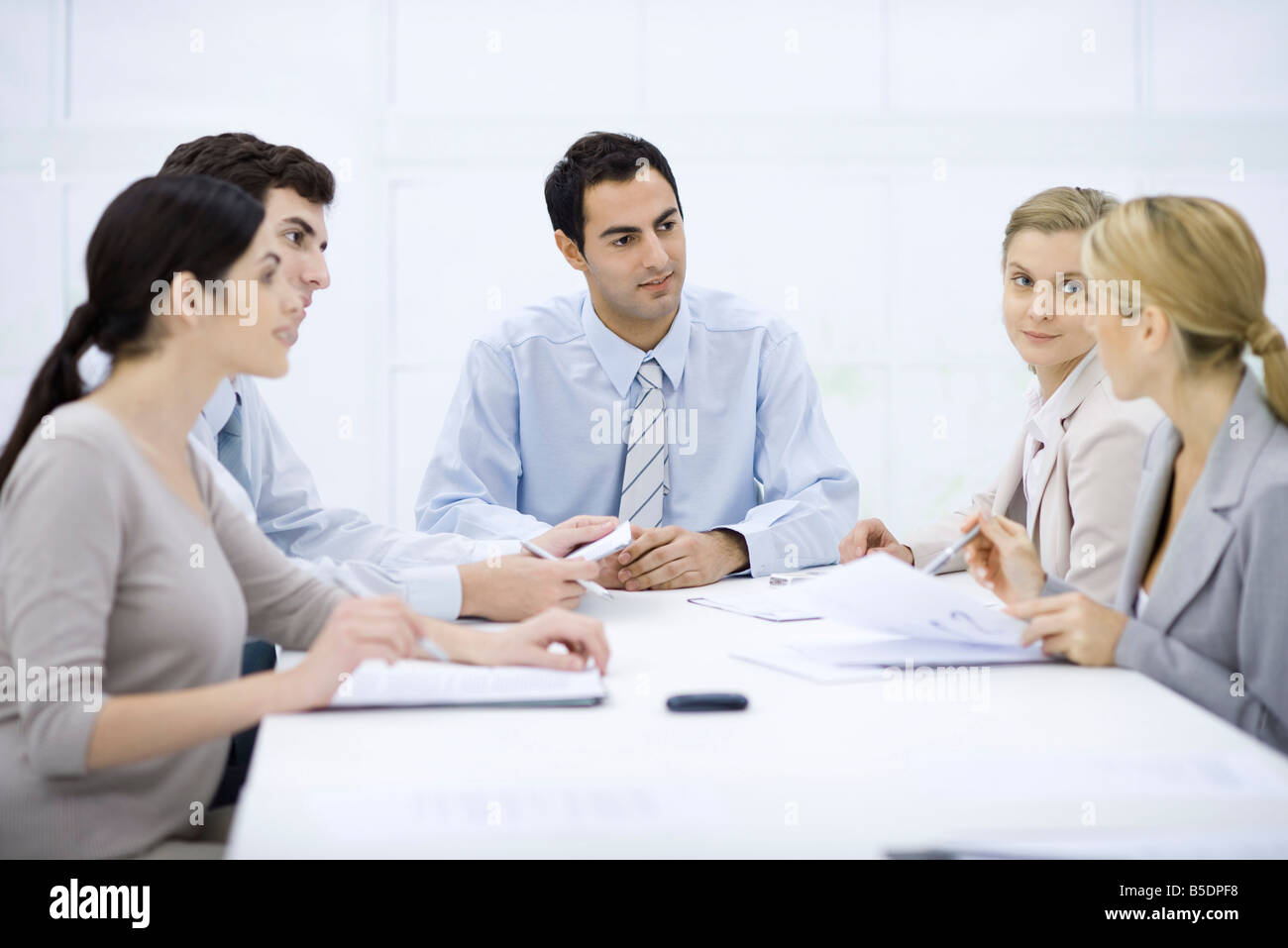 Businessman sitting with colleagues at conference table Stock Photo - Alamy