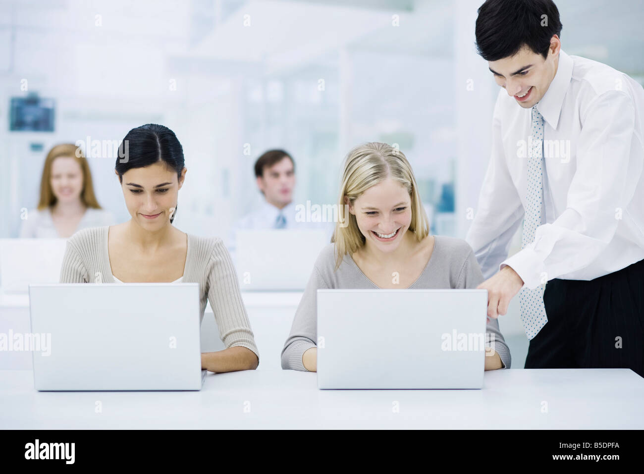 Female office worker using laptop computer, male supervisor looking ...