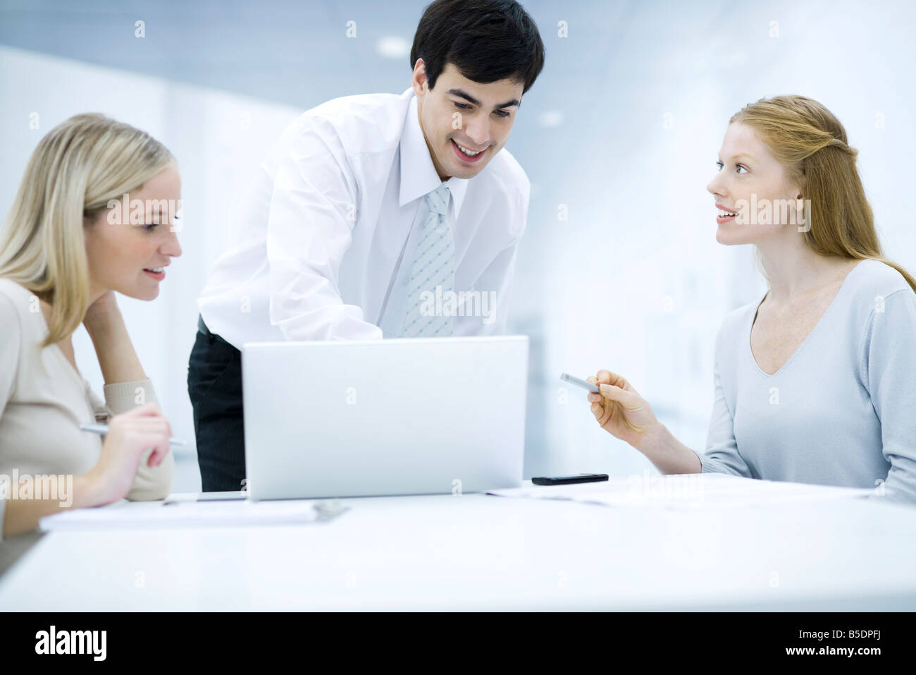 Professionals working with laptop computer together Stock Photo - Alamy