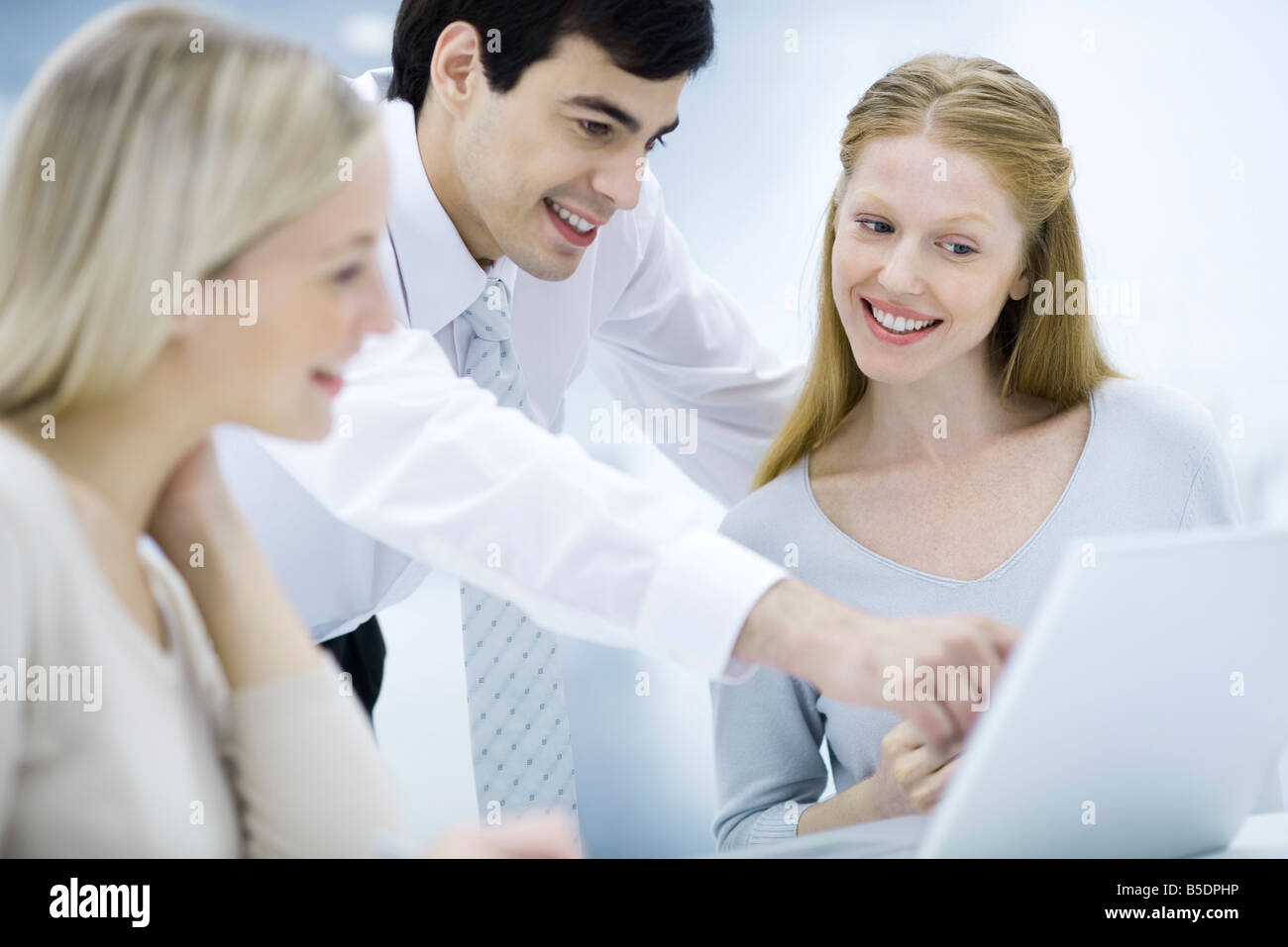 Professional man looking over female colleague's shoulder, pointing at ...