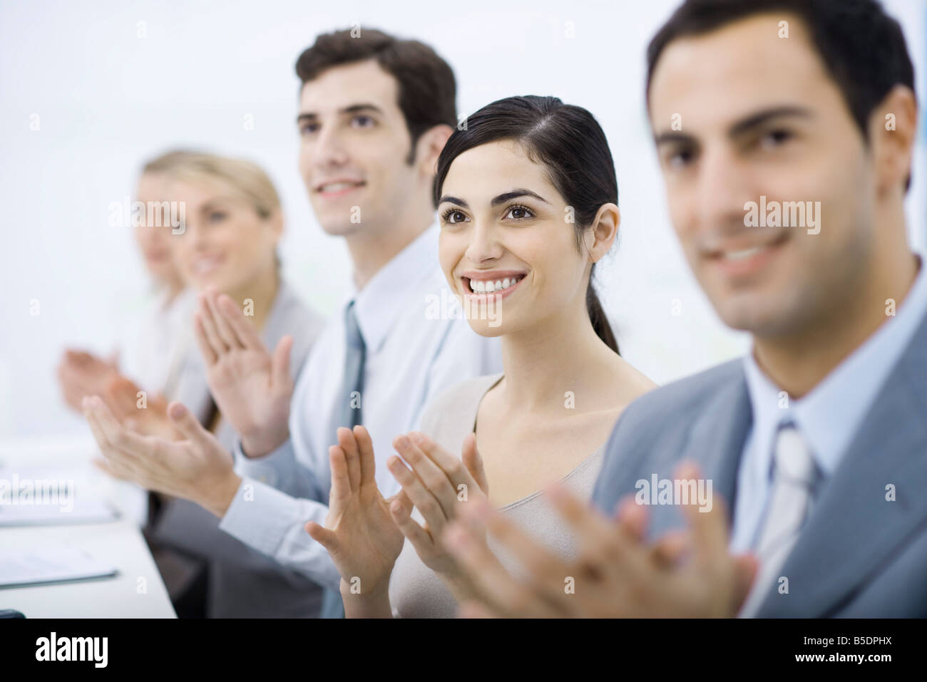 Group of professionals clapping, smiling, focus on one woman Stock ...