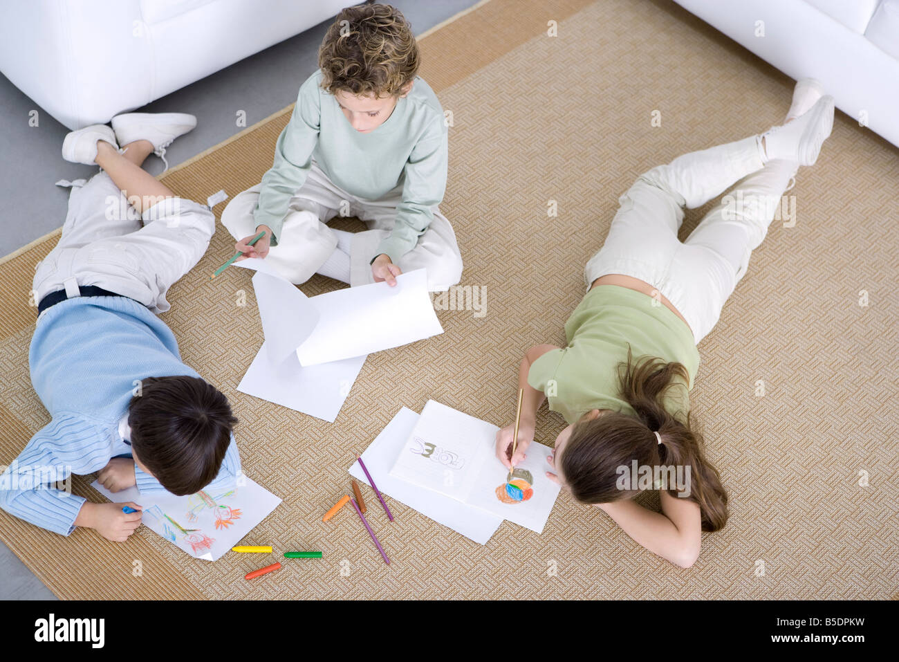 Three children coloring on the floor, high angle view Stock Photo - Alamy