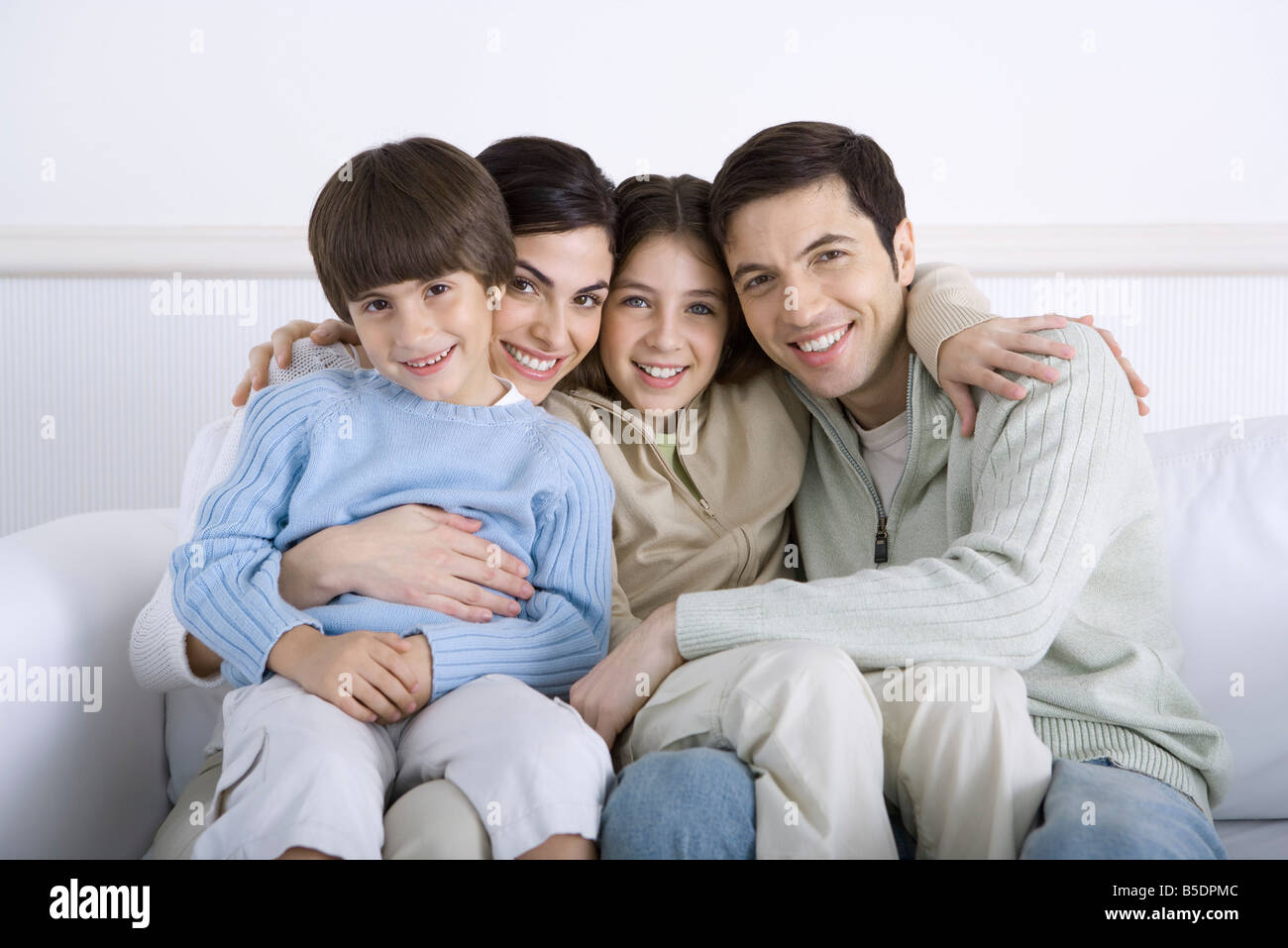Parents and two children sitting together on sofa, portrait Stock Photo ...