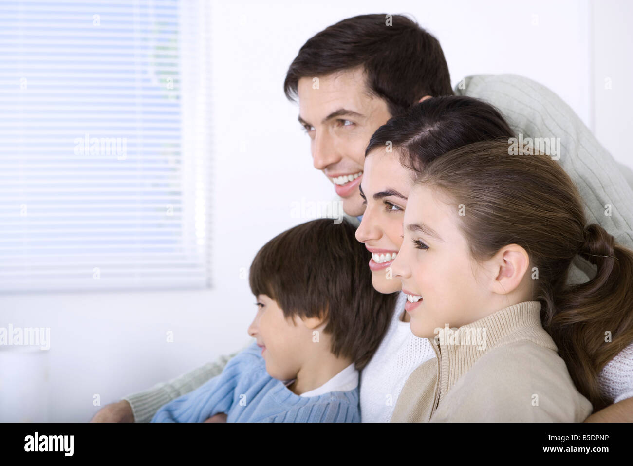 Family smiling at looking away together, side view Stock Photo - Alamy