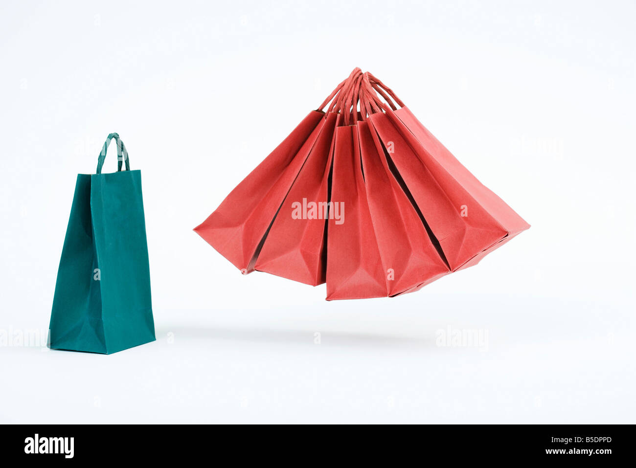 Group of red shopping bags floating in midair beside single blue bag ...