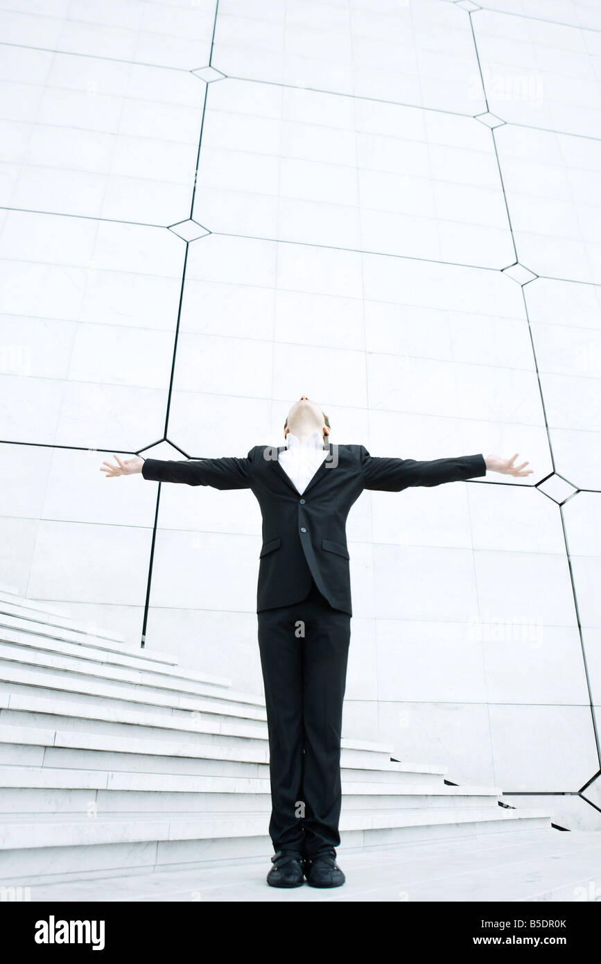 Business woman standing at foot of stairs with arms outstretched ...