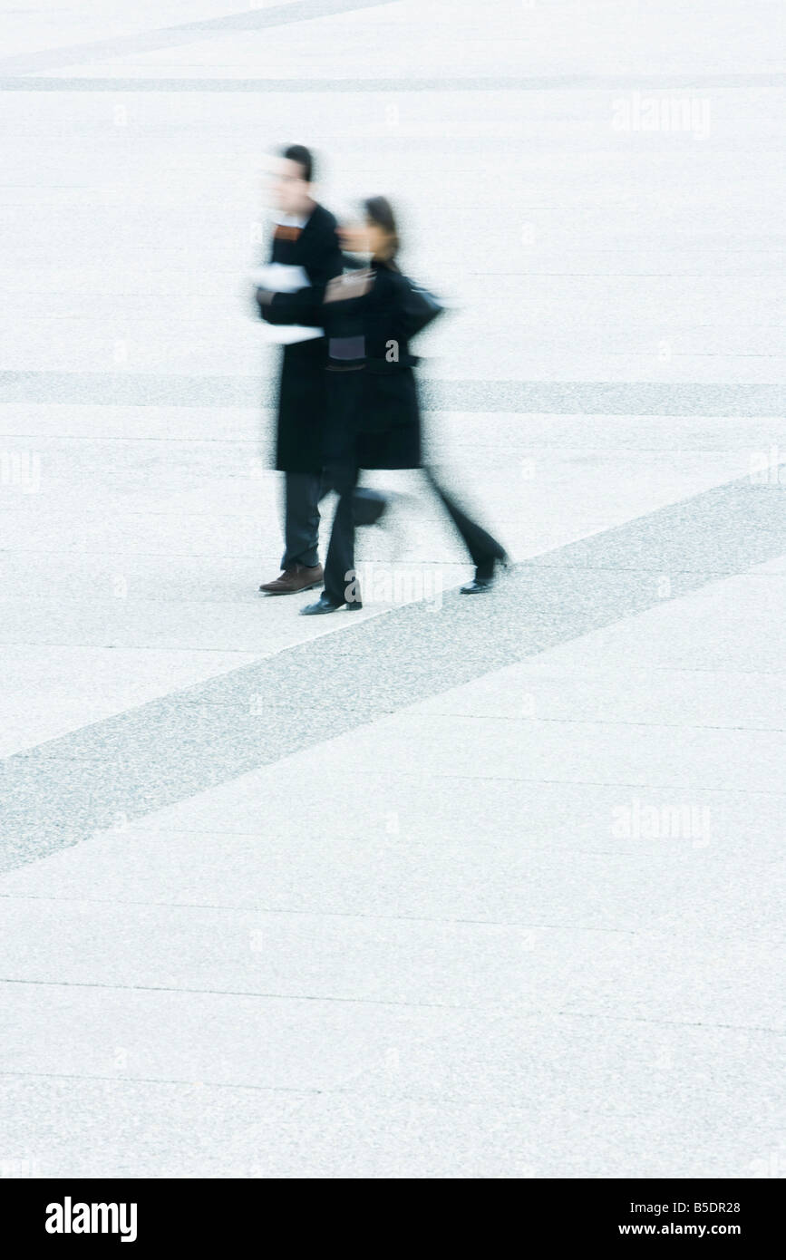 Businessman and businesswoman walking together across public square ...