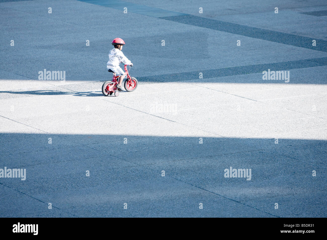 Child riding bicycle alone in public square Stock Photo - Alamy