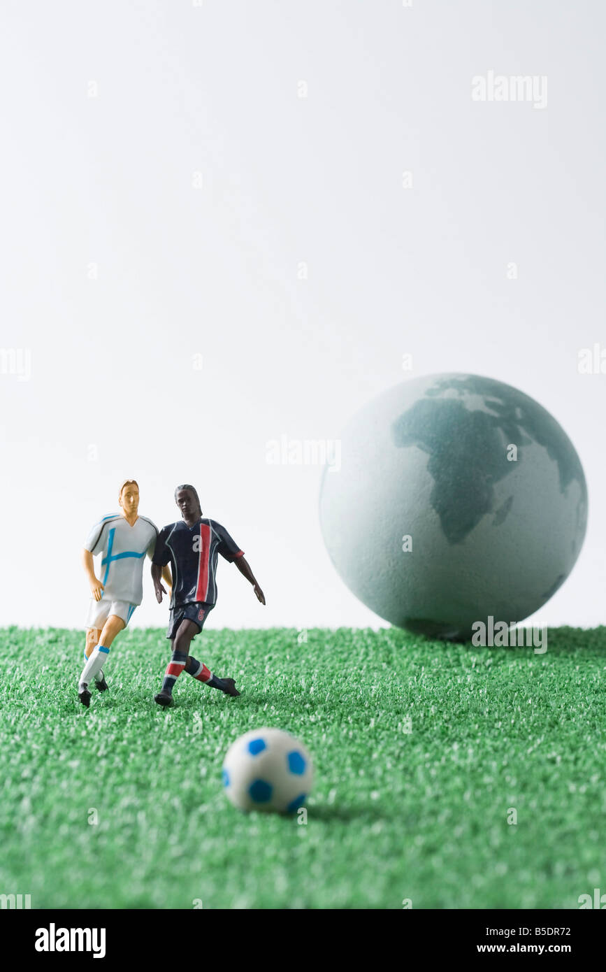Miniature soccer players chasing soccer ball, globe in background Stock ...