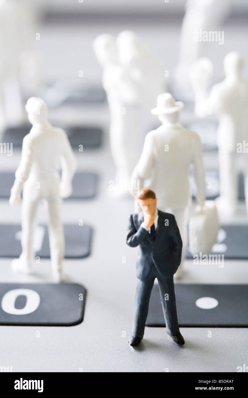 Miniature man figure in suit standing with hand under chin, white ...