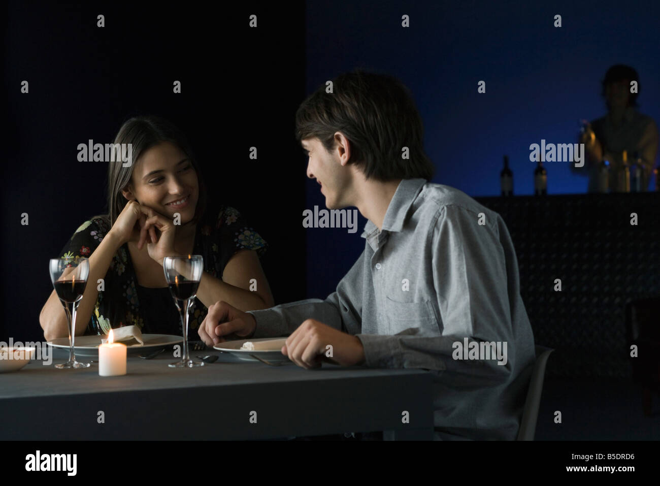 Couple having conversation over dinner at restaurant, smiling at each ...