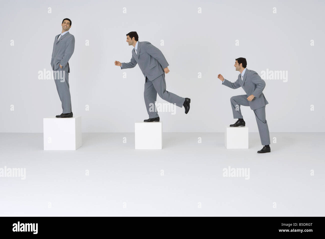 Identical businessmen climbing gradually larger blocks Stock Photo - Alamy