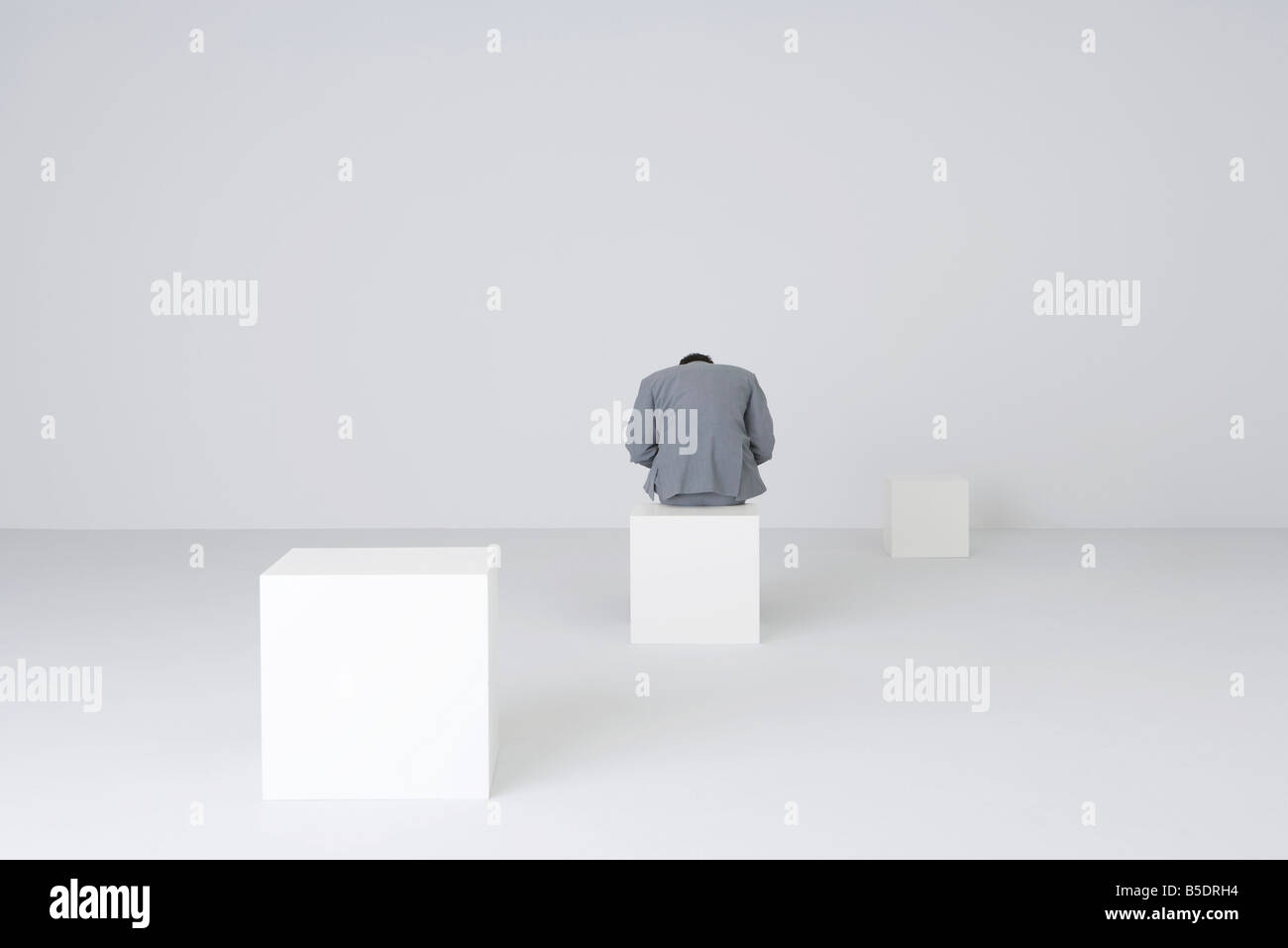 Businessman sitting on block with head down, rear view Stock Photo - Alamy