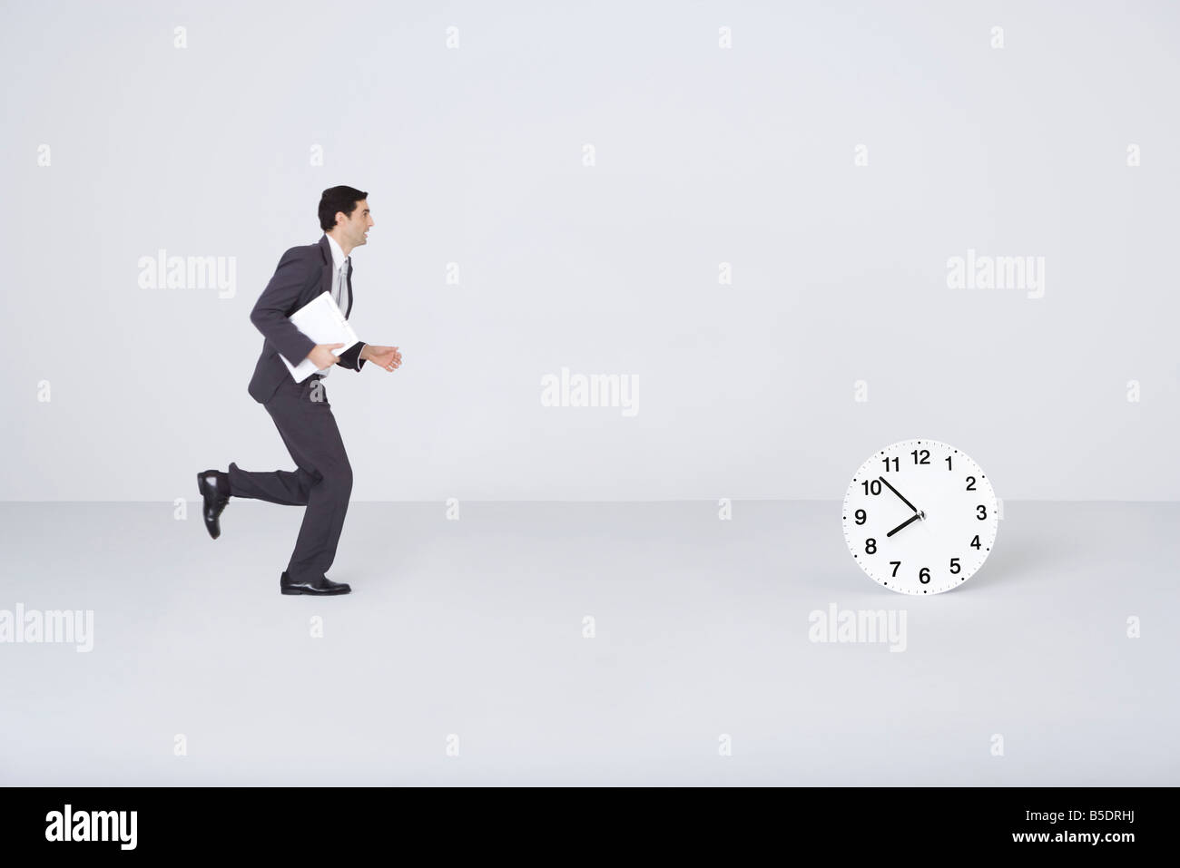 Businessman running toward clock Stock Photo - Alamy