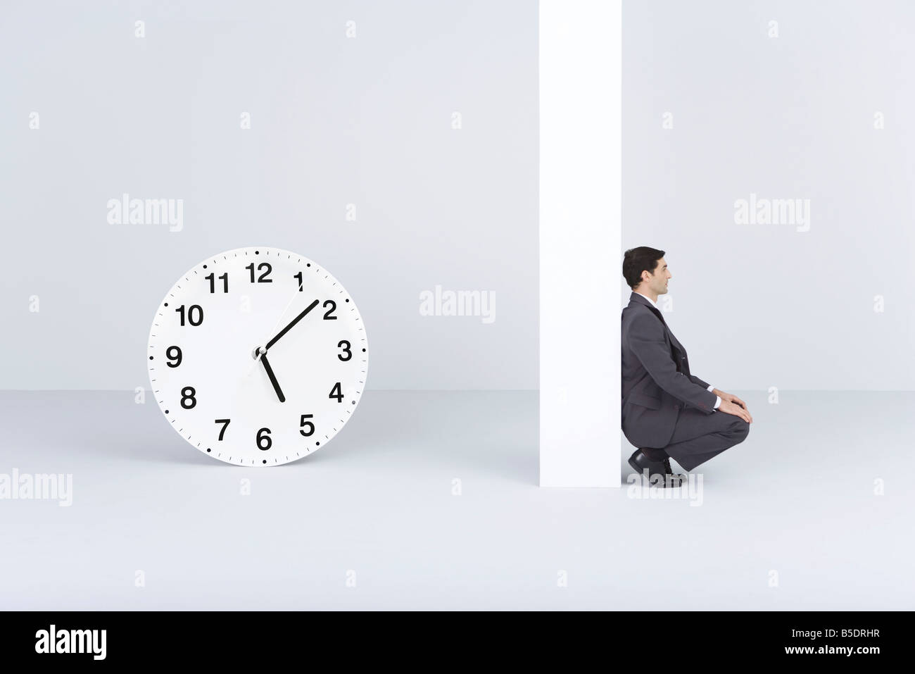Businessman waiting, near oversized clock Stock Photo - Alamy