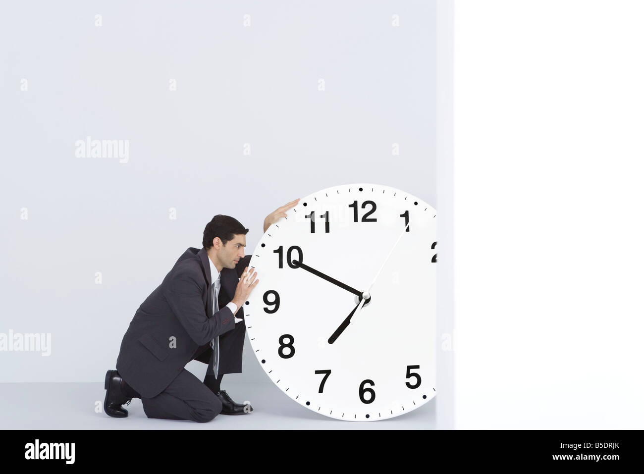 Businessman staring at oversized clock Stock Photo - Alamy