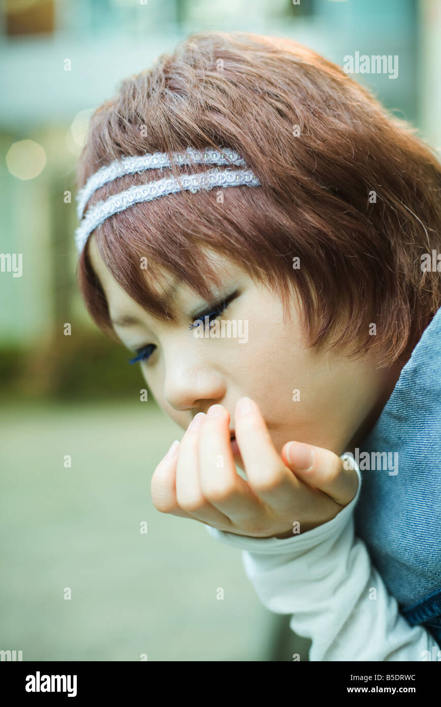 Young woman resting chin on hand, looking down Stock Photo - Alamy