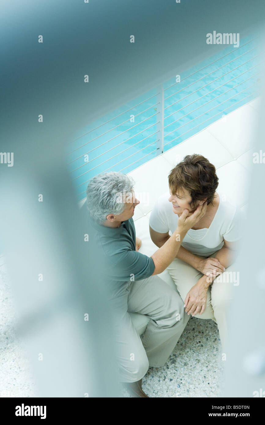 Couple sitting face to face, man touching woman's cheek, high angle ...
