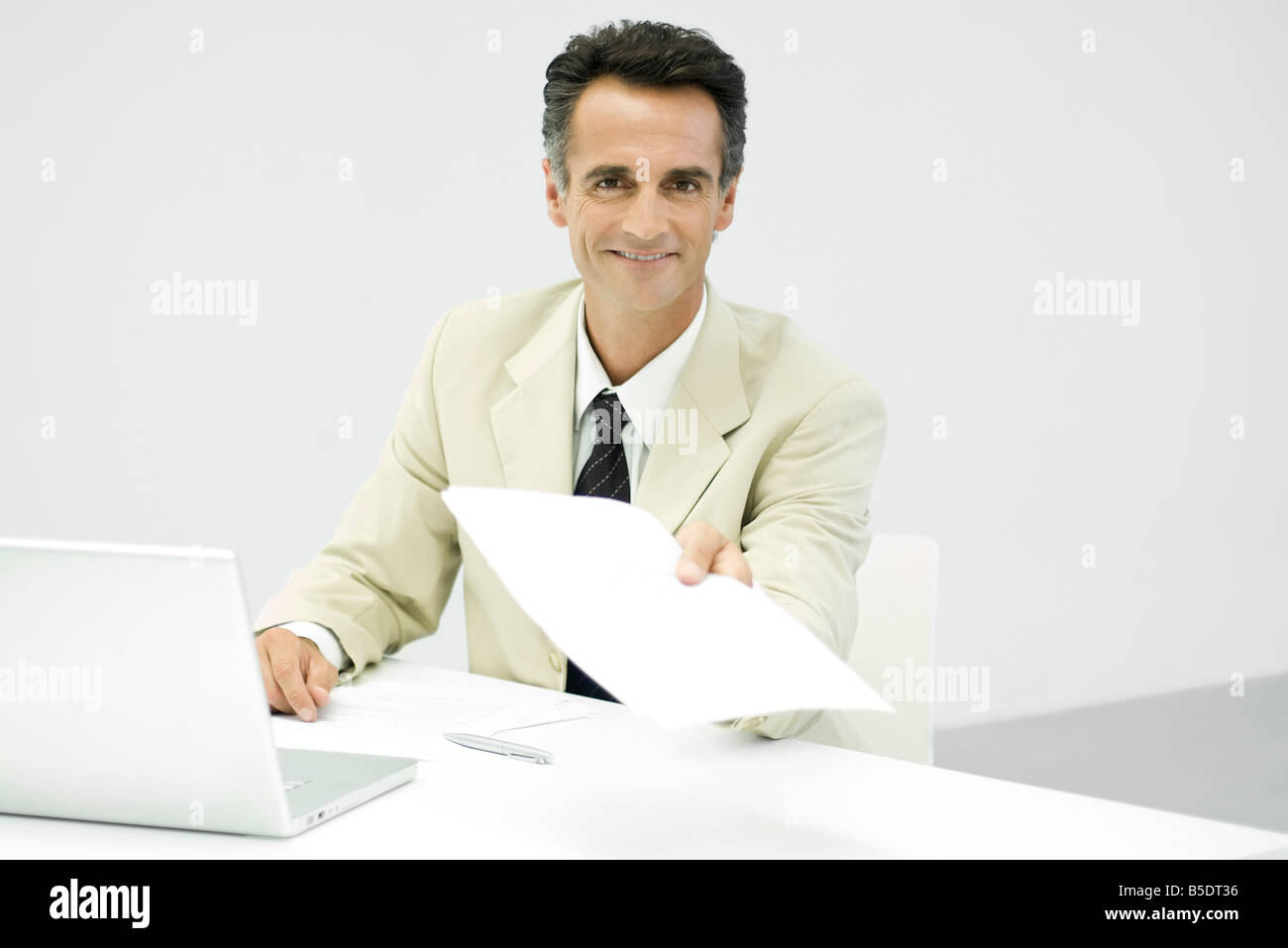 Businessman holding out document, smiling at camera Stock Photo - Alamy