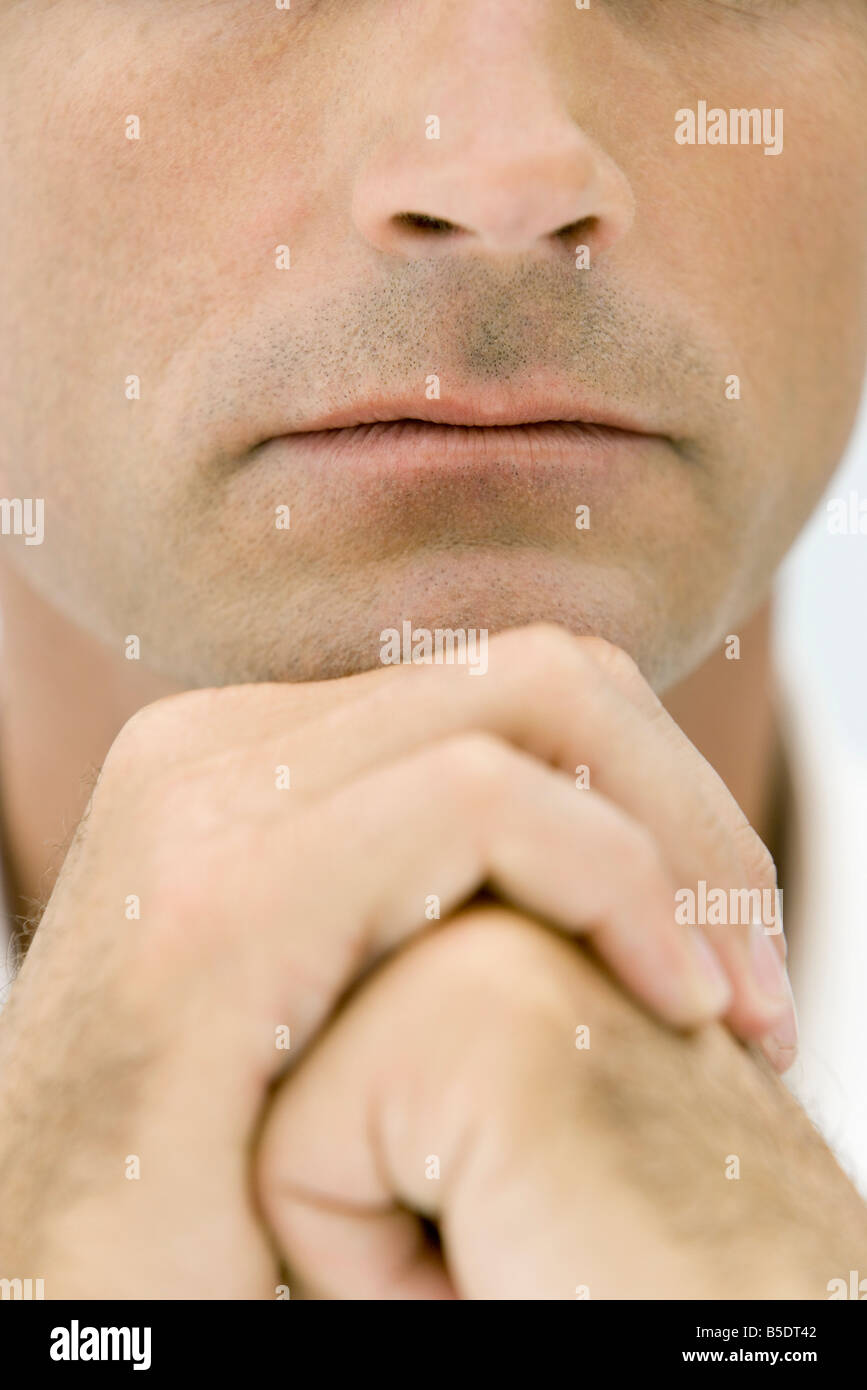 Man holding hands together under chin, cropped view Stock Photo - Alamy