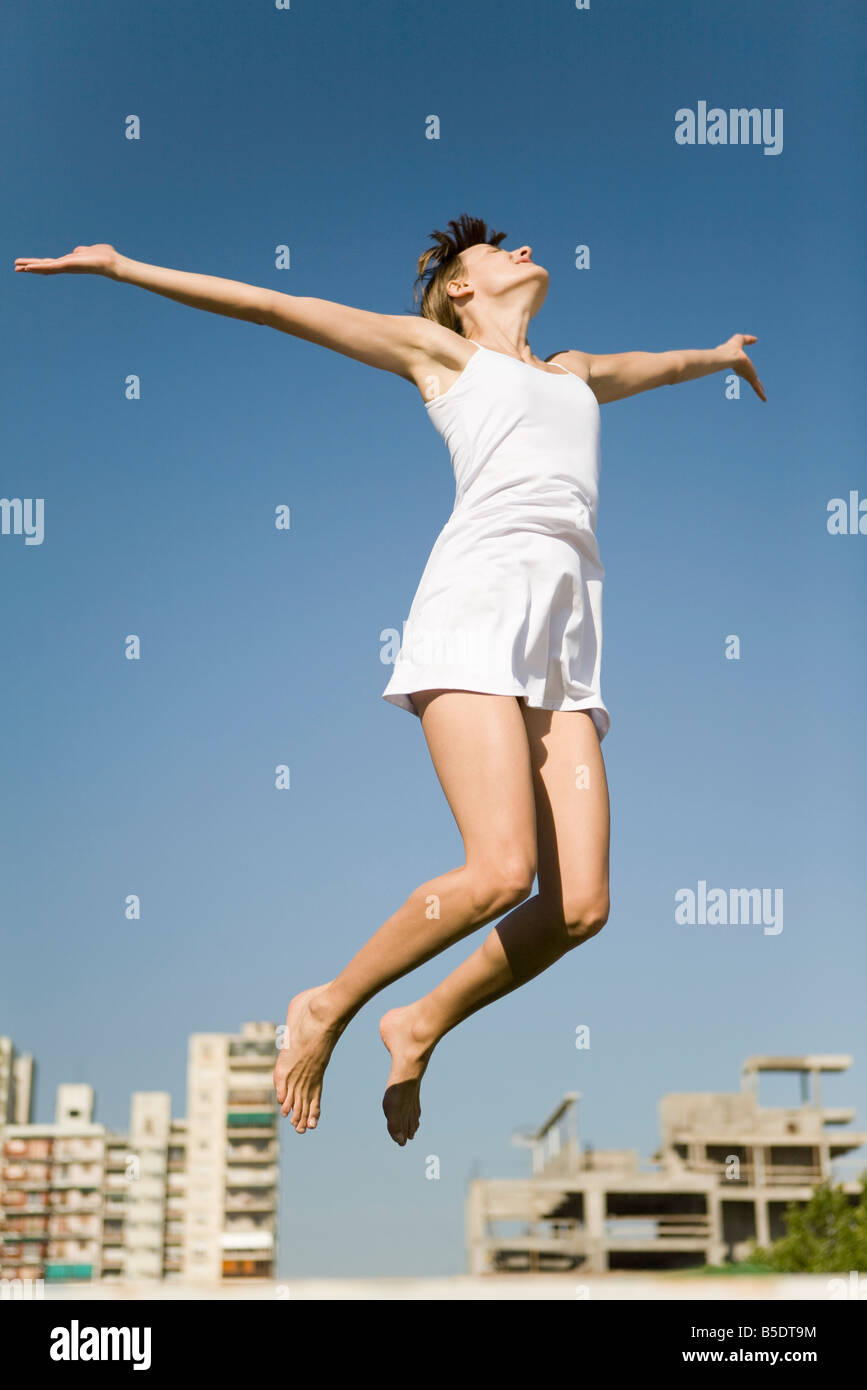 Woman jumping in midair, arms out, head back Stock Photo - Alamy