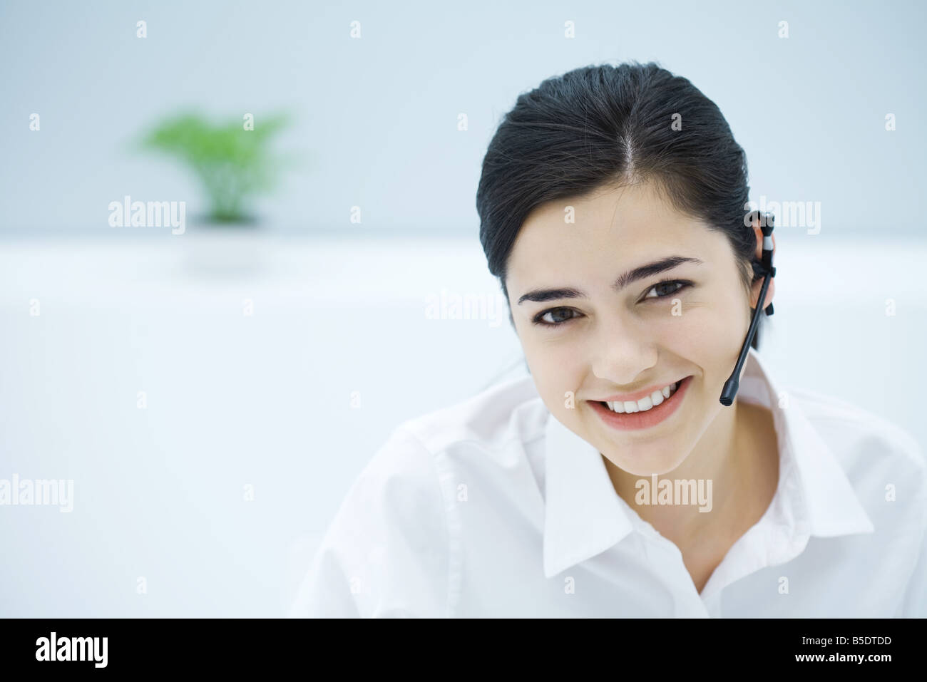Young woman wearing headset, smiling at camera, portrait Stock Photo ...