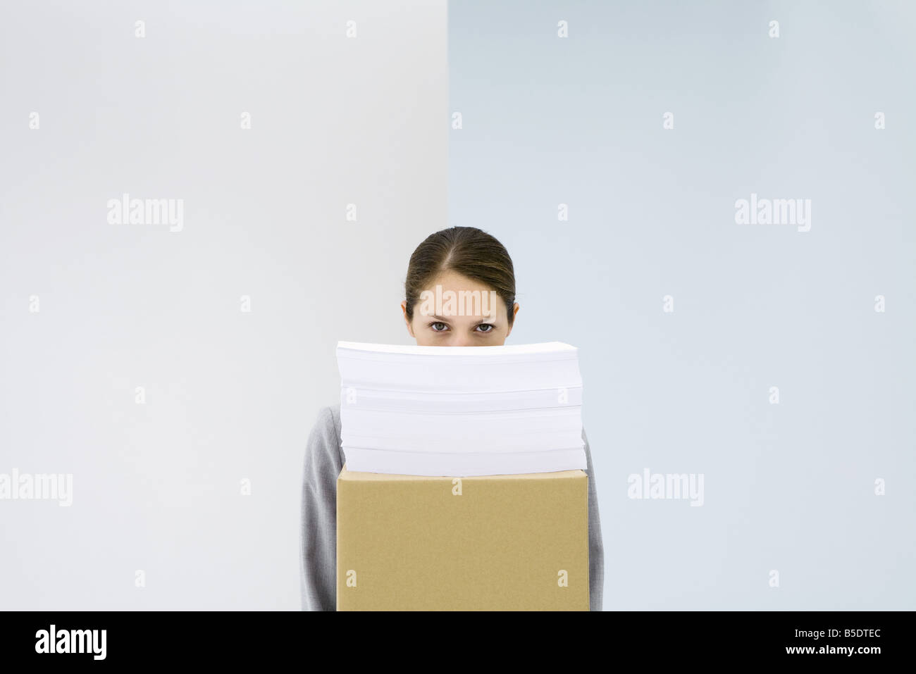 Woman peeking over stack of paper on top of cardboard box Stock Photo ...