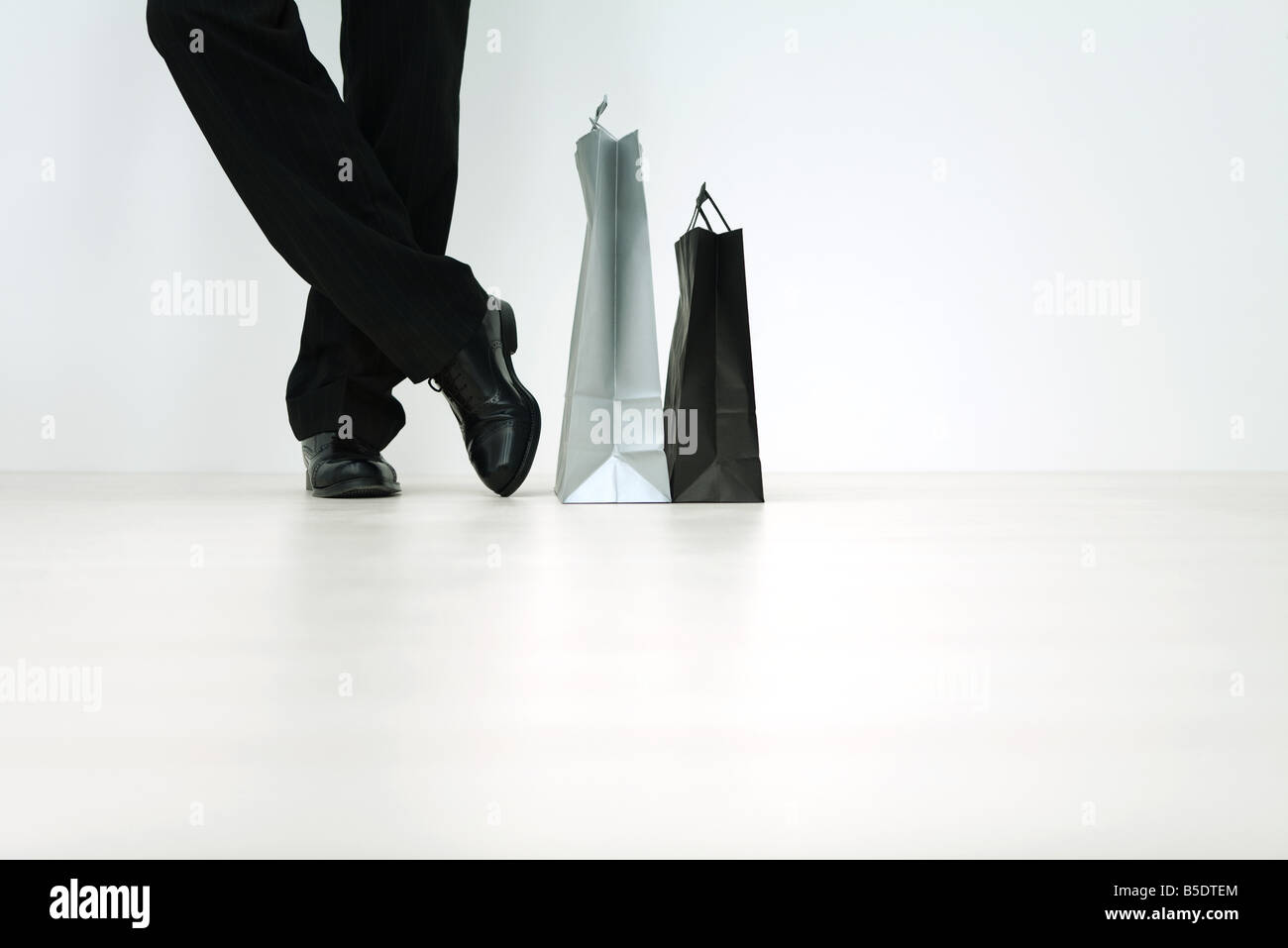 Man standing next to shopping bags, cropped view of feet, low angle ...