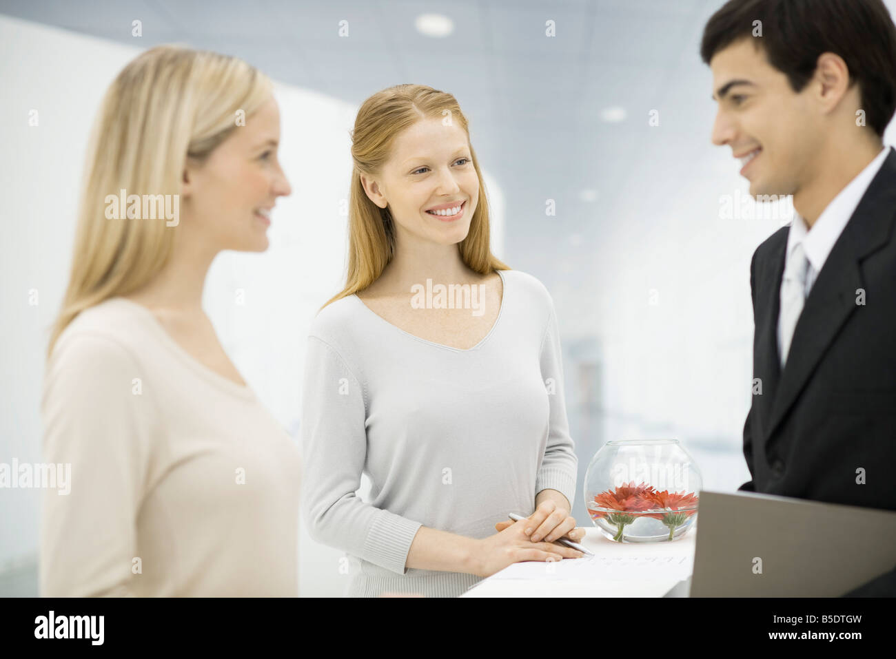 Businessman talking with two receptionists at counter, focus on women ...