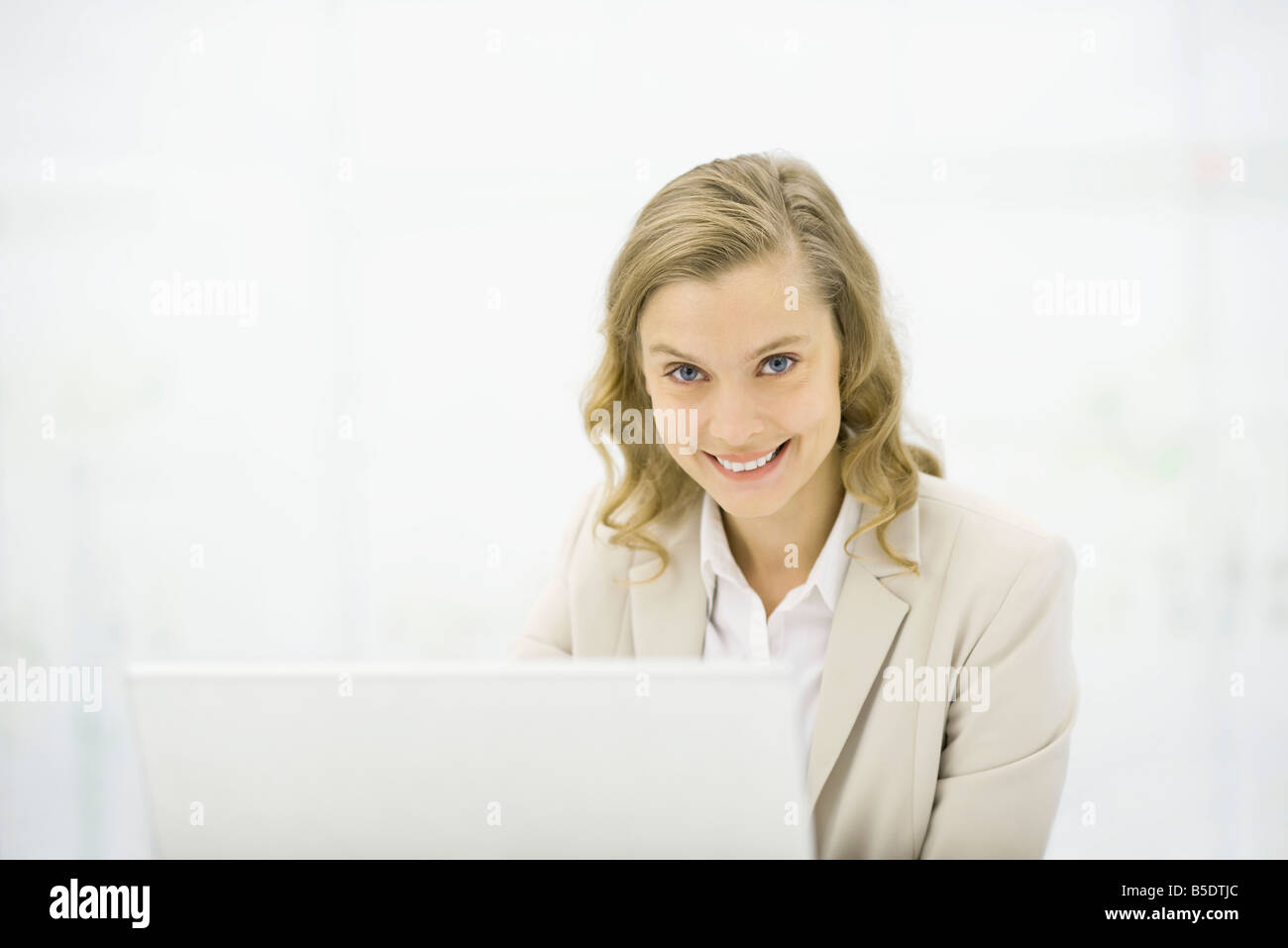 Professional woman using laptop, smiling at camera Stock Photo - Alamy