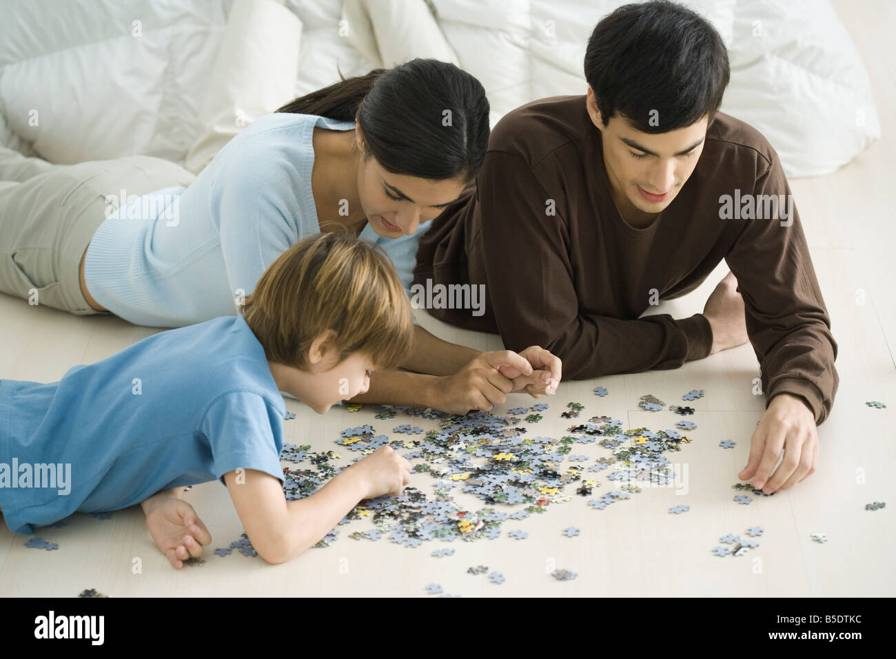 Family lying on floor, putting together jigsaw puzzle Stock Photo - Alamy