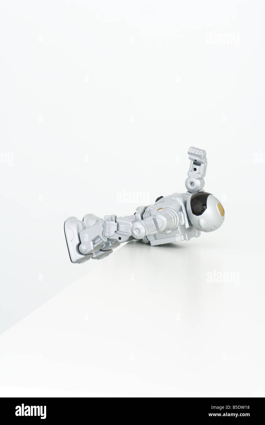 Toy robot resting precariously on edge of table Stock Photo - Alamy