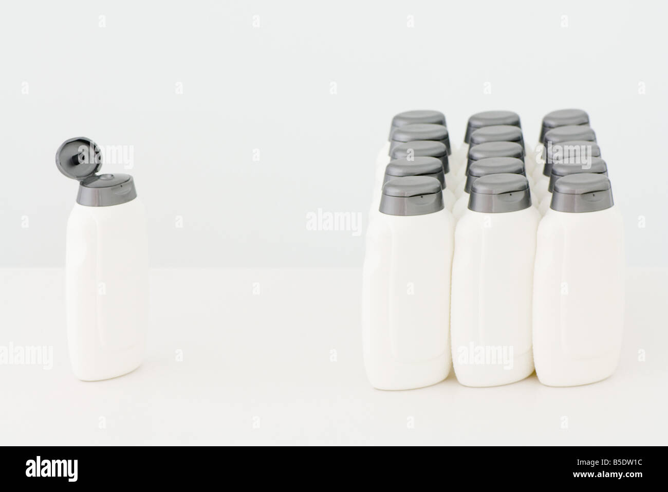 Single plastic bottle with open lid facing group of closed bottles ...