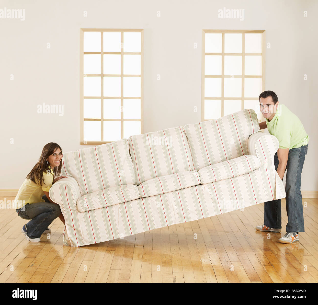 Mid-Adult Couple Moving Sofa Stock Photo - Alamy