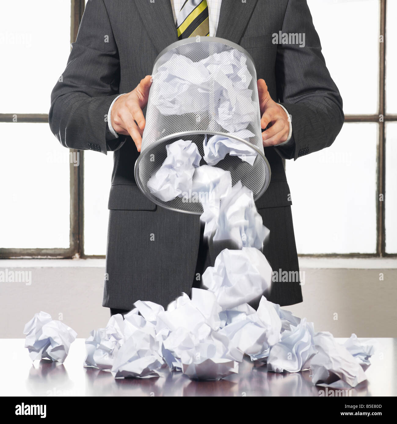 Businessman pouring trash over desk Stock Photo - Alamy
