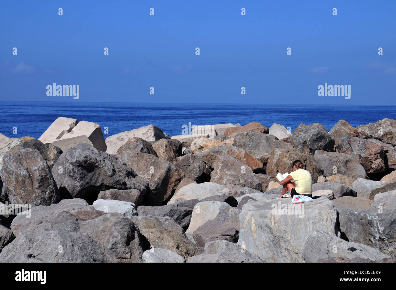 Solitary woman reading a book on coastal rocks Gran Canaria Stock Photo ...