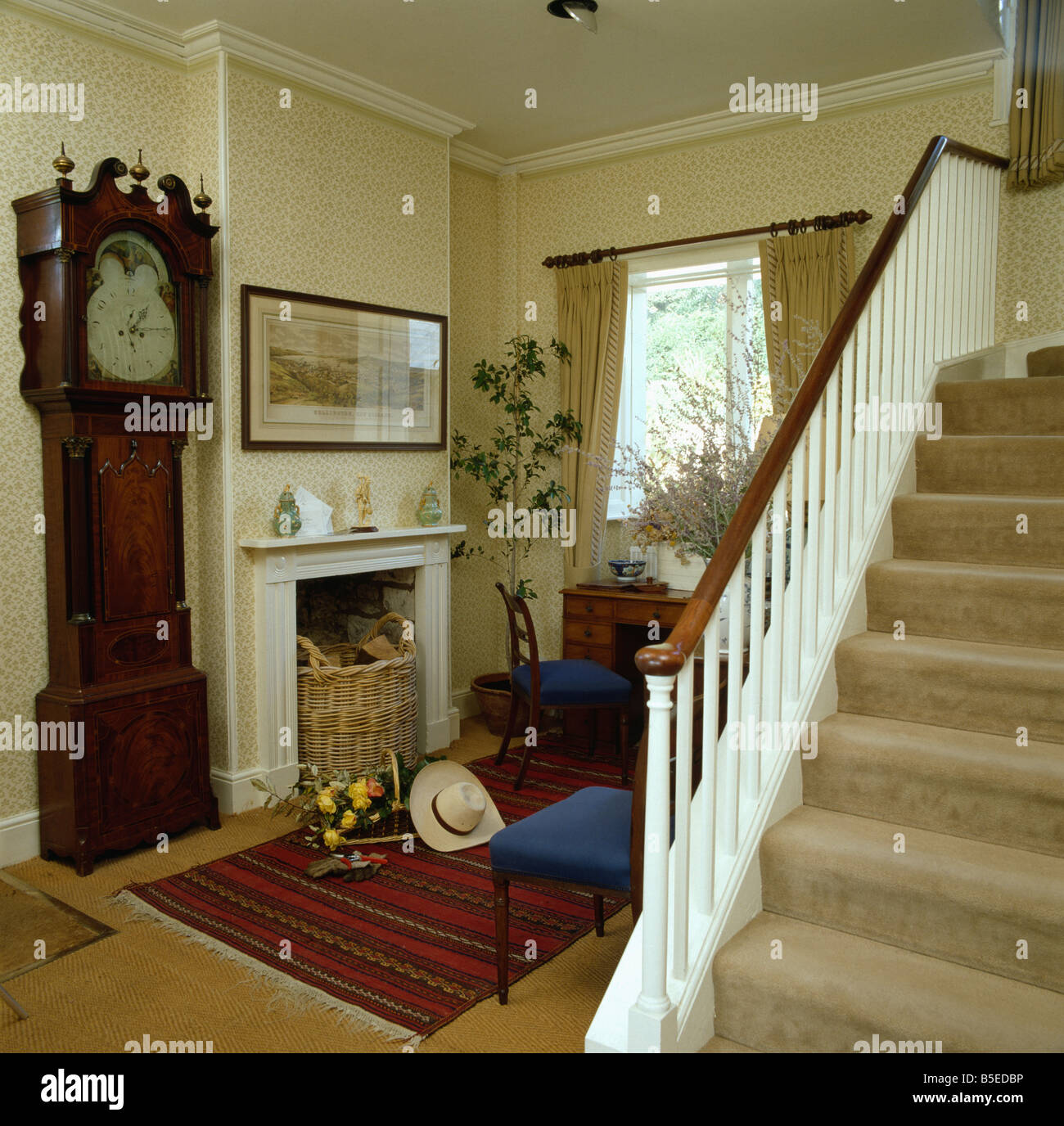 Antique longcase clock beside fireplace in small cream cottage hall ...