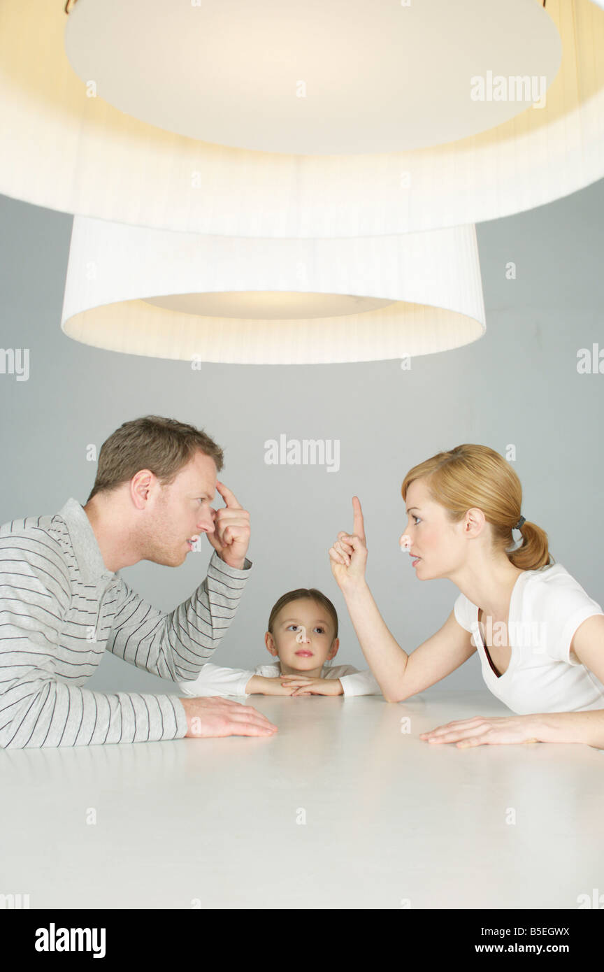 Couple arguing at table, girl in background Stock Photo - Alamy