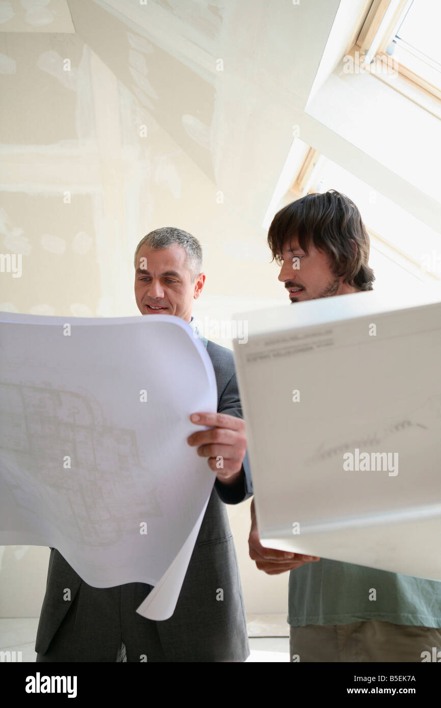 Two men looking at construction plan Stock Photo - Alamy